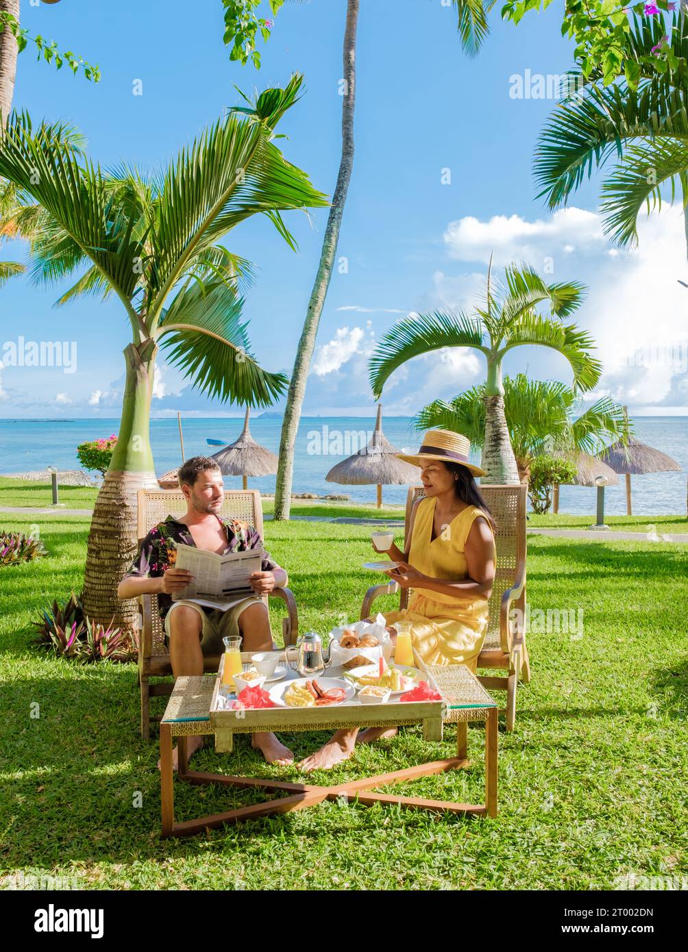 Man and Woman having breakfast in a garden with palm trees on a ...