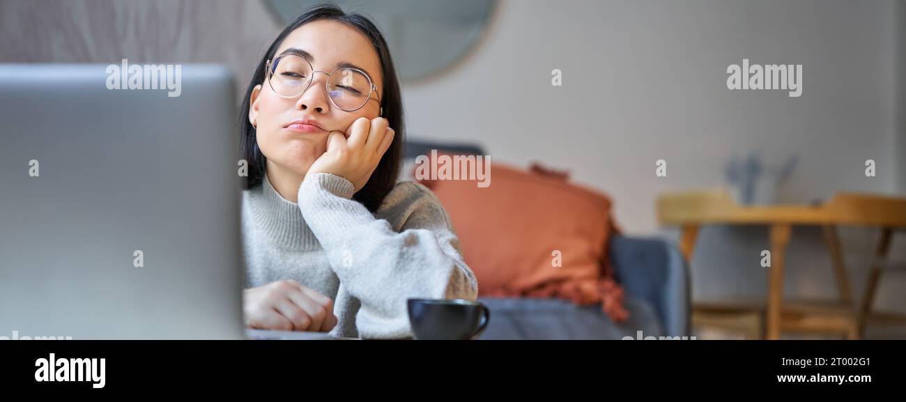 Portrait of korean girl sits bored, student looks gloomy at laptop ...