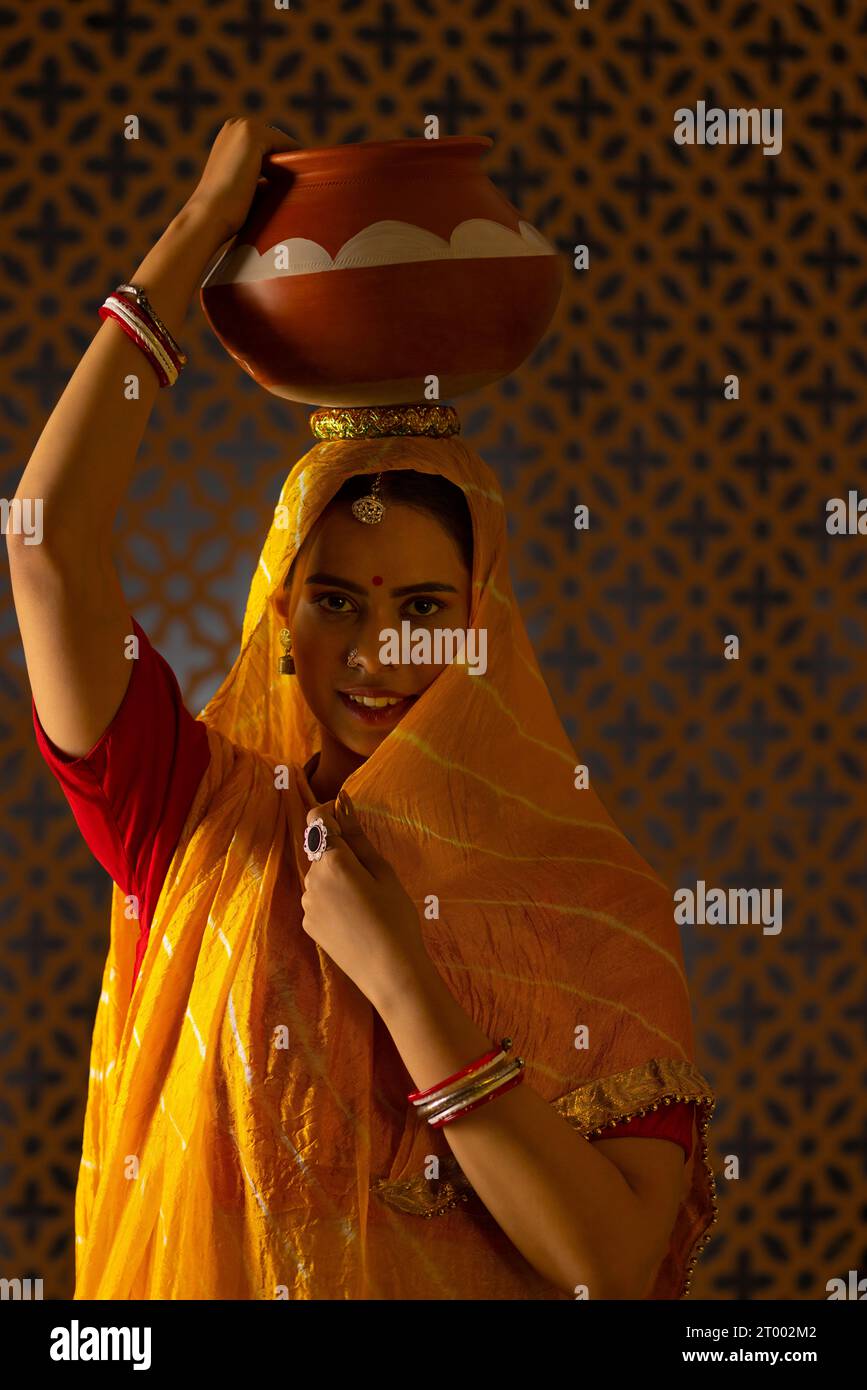 Portrait of a happy Rajasthani woman carrying clay pot on her head ...