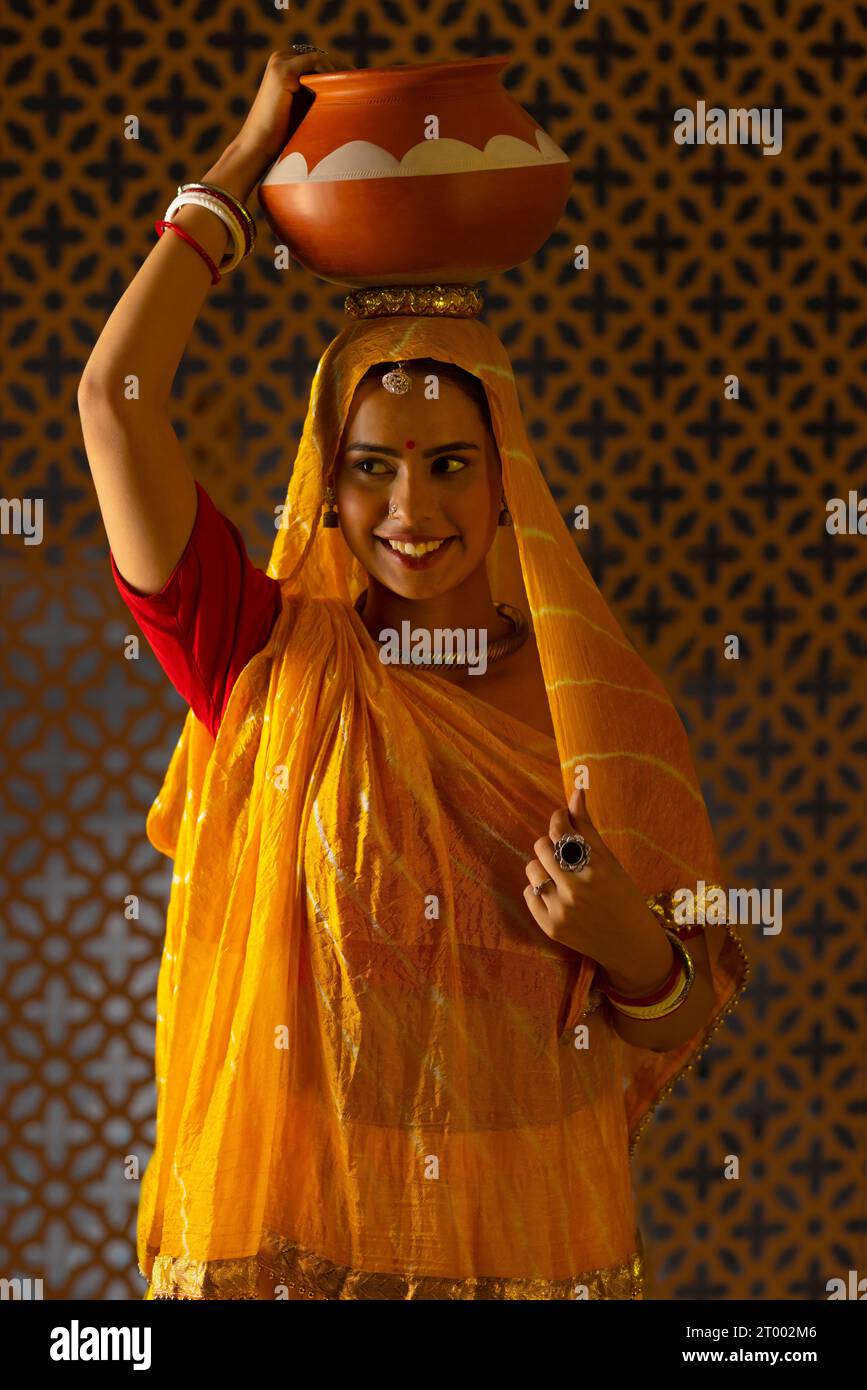 A happy Rajasthani woman carrying clay pot on her head Stock Photo - Alamy