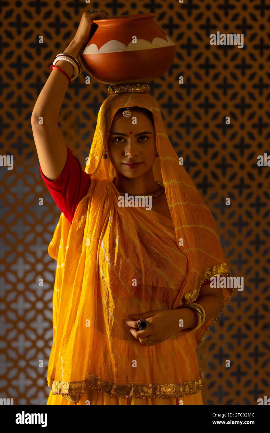 Portrait of a happy Rajasthani woman carrying clay pot on her head ...