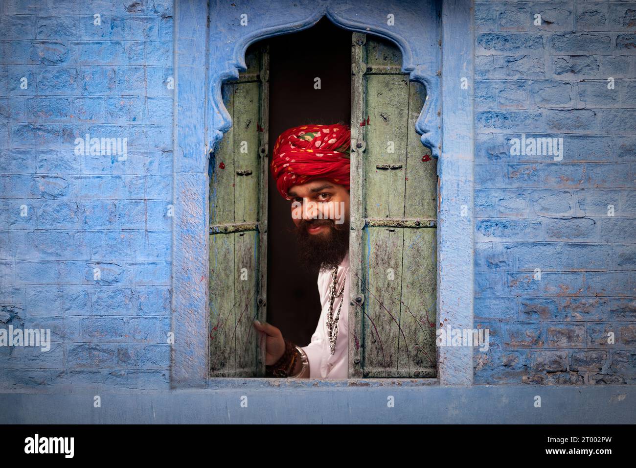 Rajasthani young man peeking out through window Stock Photo - Alamy