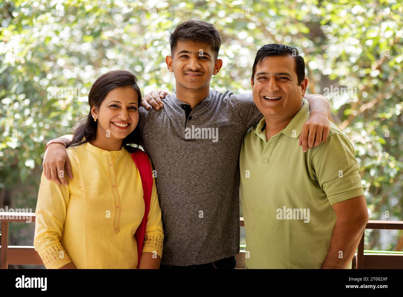 Happy parents with their teenage son standing together on balcony Stock ...