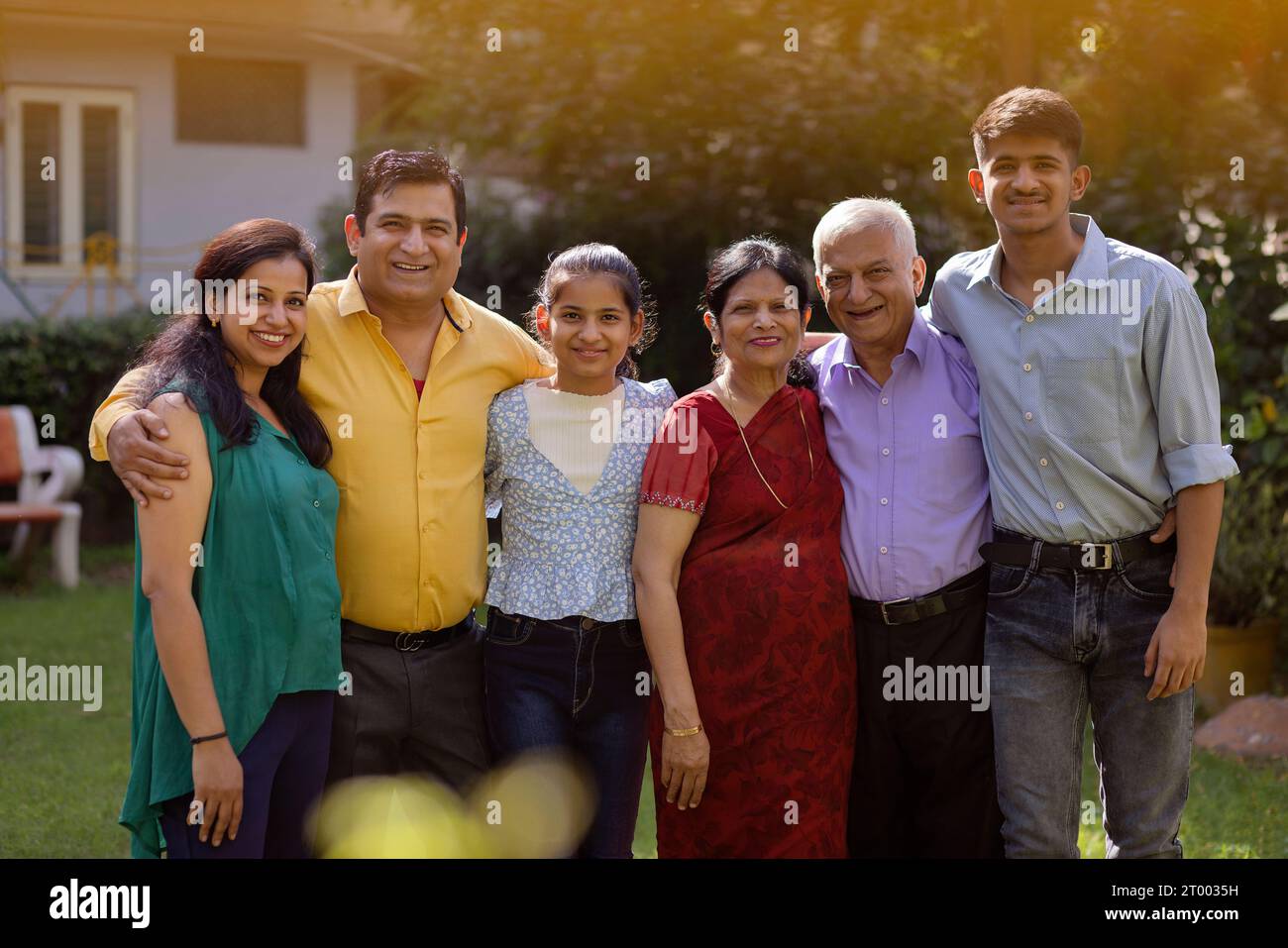 Multi generation happy Indian family standing together in backyard ...