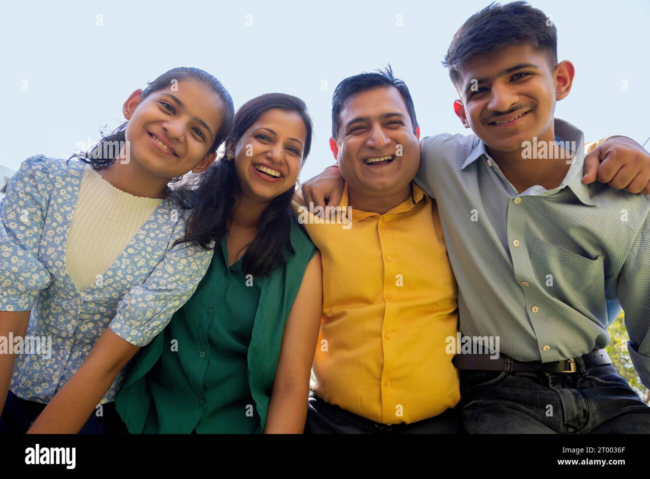 Low angle view of happy Indian family standing together in backyard ...
