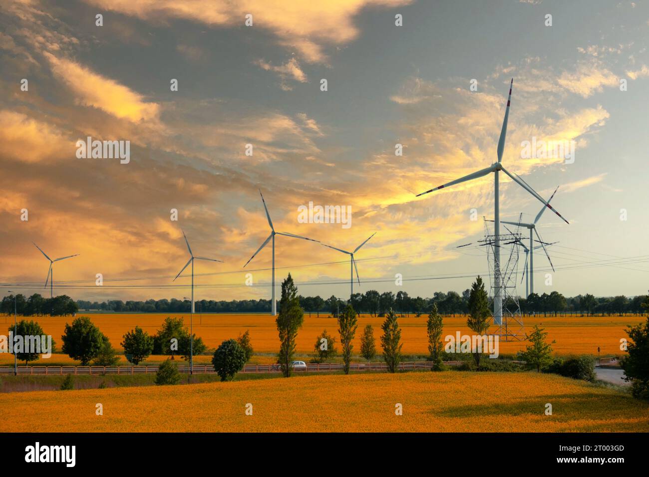Wind turbine on grassy yellow field against cloudy blue sky in rural ...