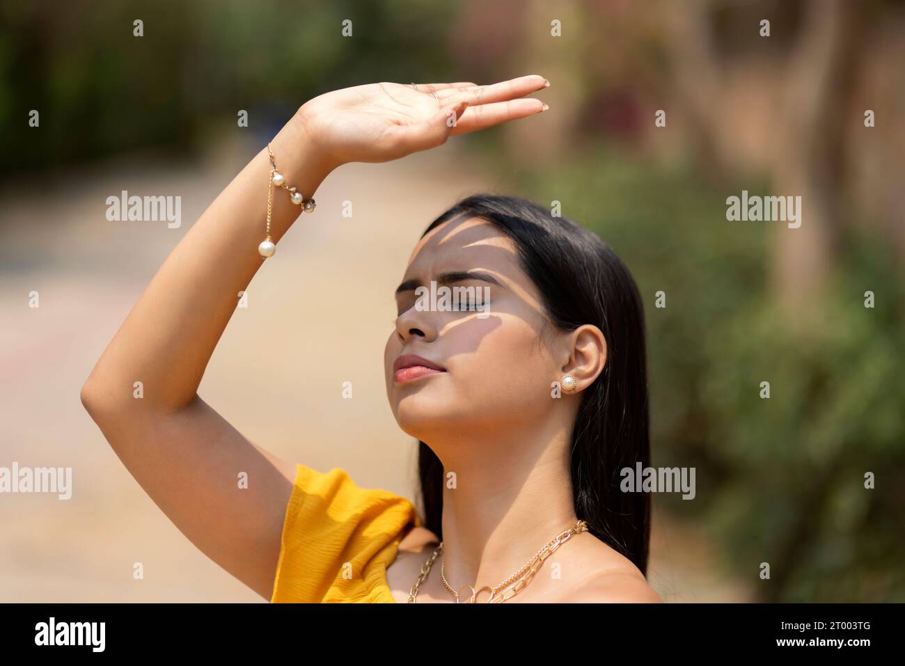 Woman covering her face from sun with her hand in the park Stock Photo ...