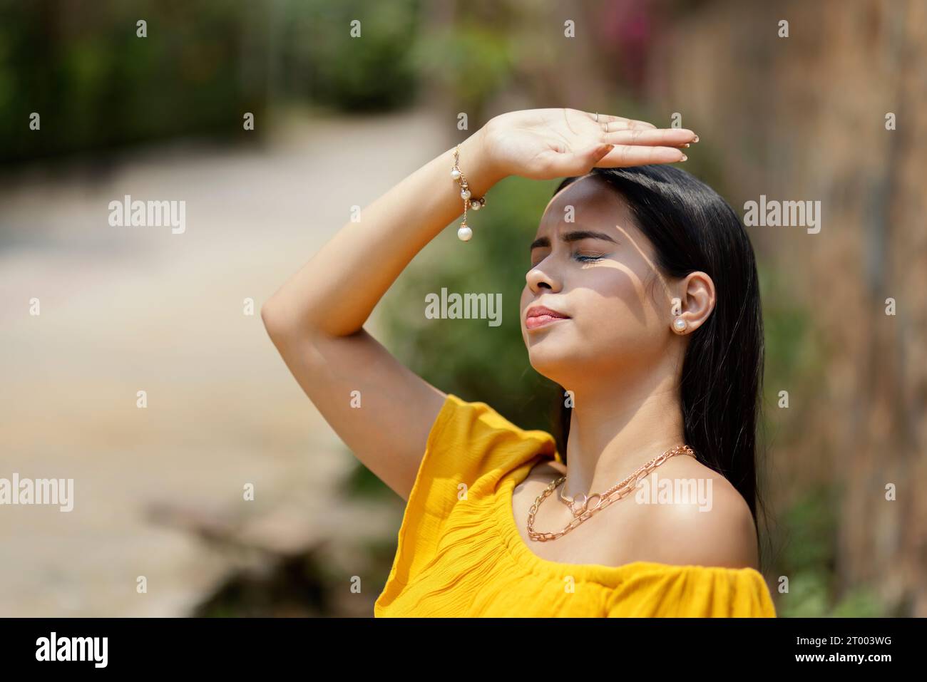 Woman covering her face from sun with her hand in the park Stock Photo ...
