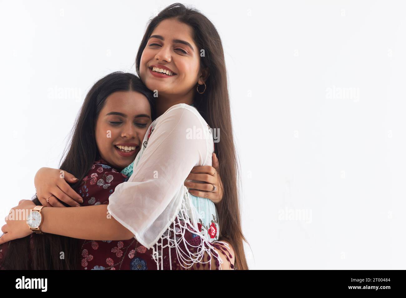 Portrait of two female friends embracing against white background Stock ...