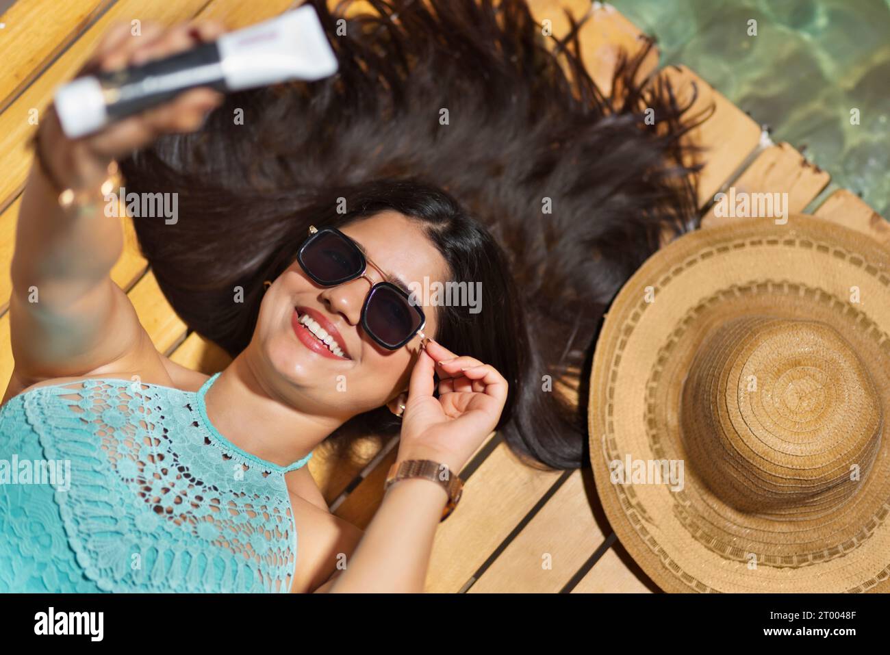 Woman sunbathing on sun lounger by swimming pool Stock Photo - Alamy