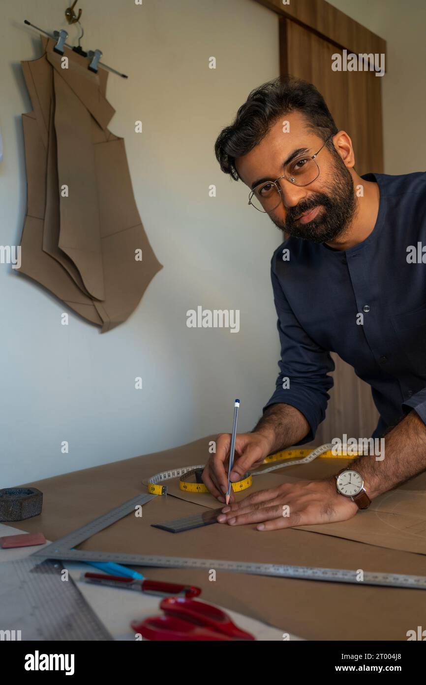 A male designer making patterns for a menswear collection in his studio ...