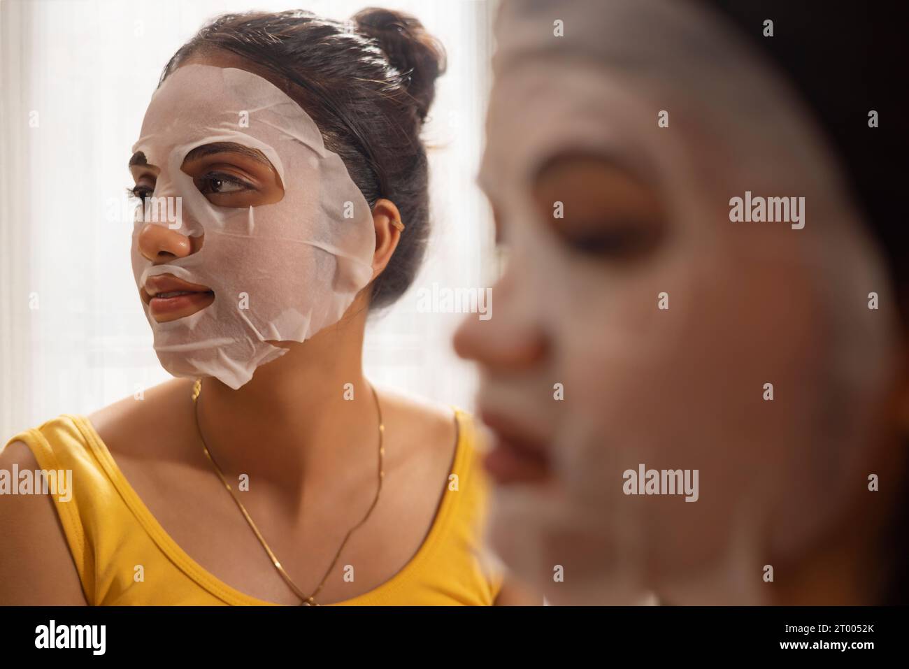 Close-up portrait of two young women with paper facial mask on their ...