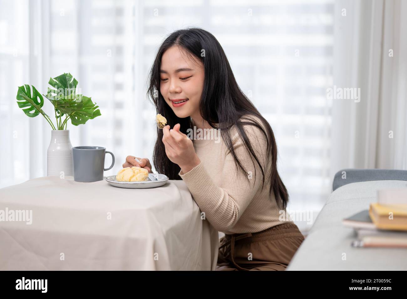A beautiful and cheerful young Asian woman enjoying her breakfast ...