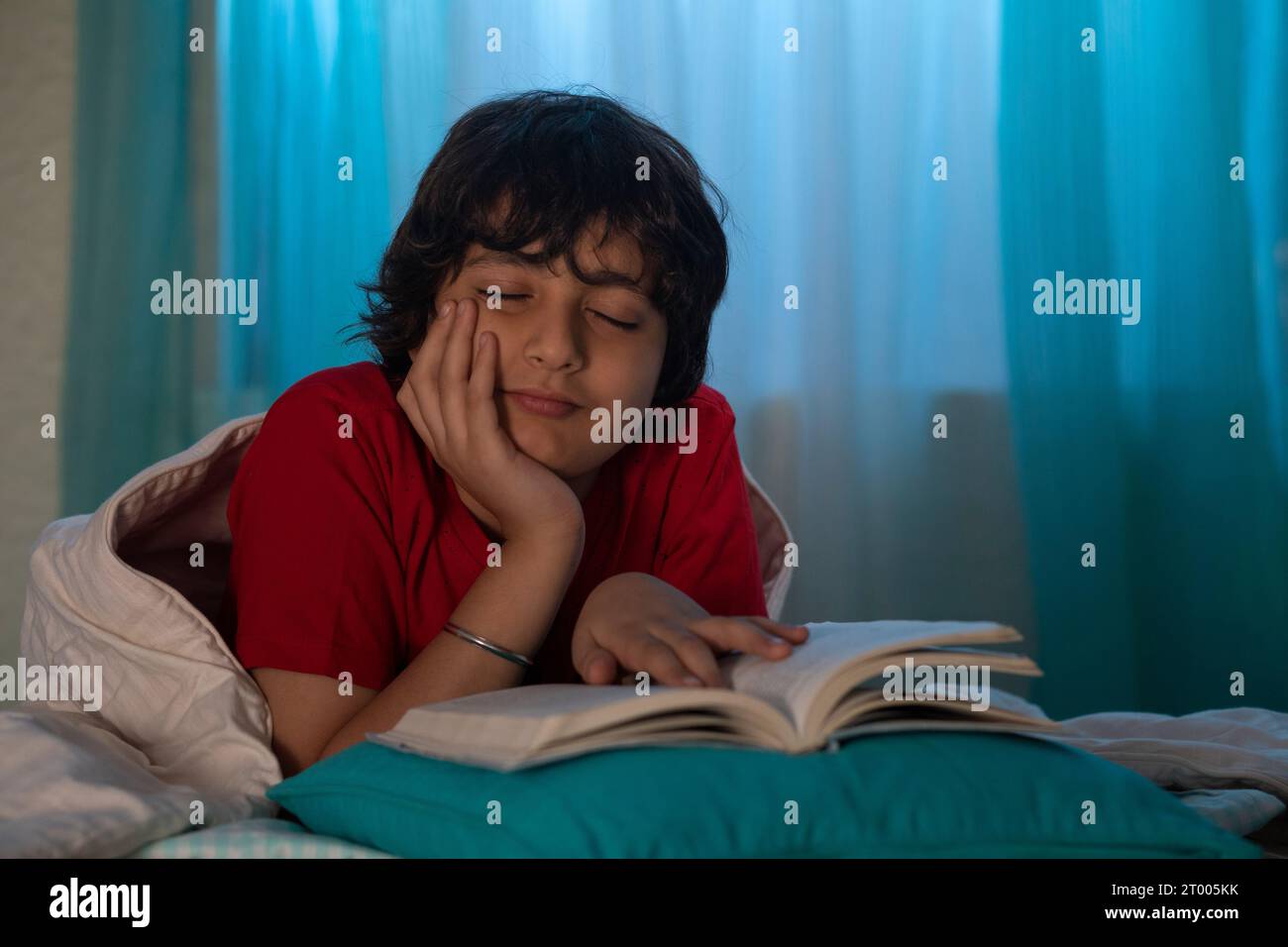 Boy thinking while reading a book on bed Stock Photo - Alamy