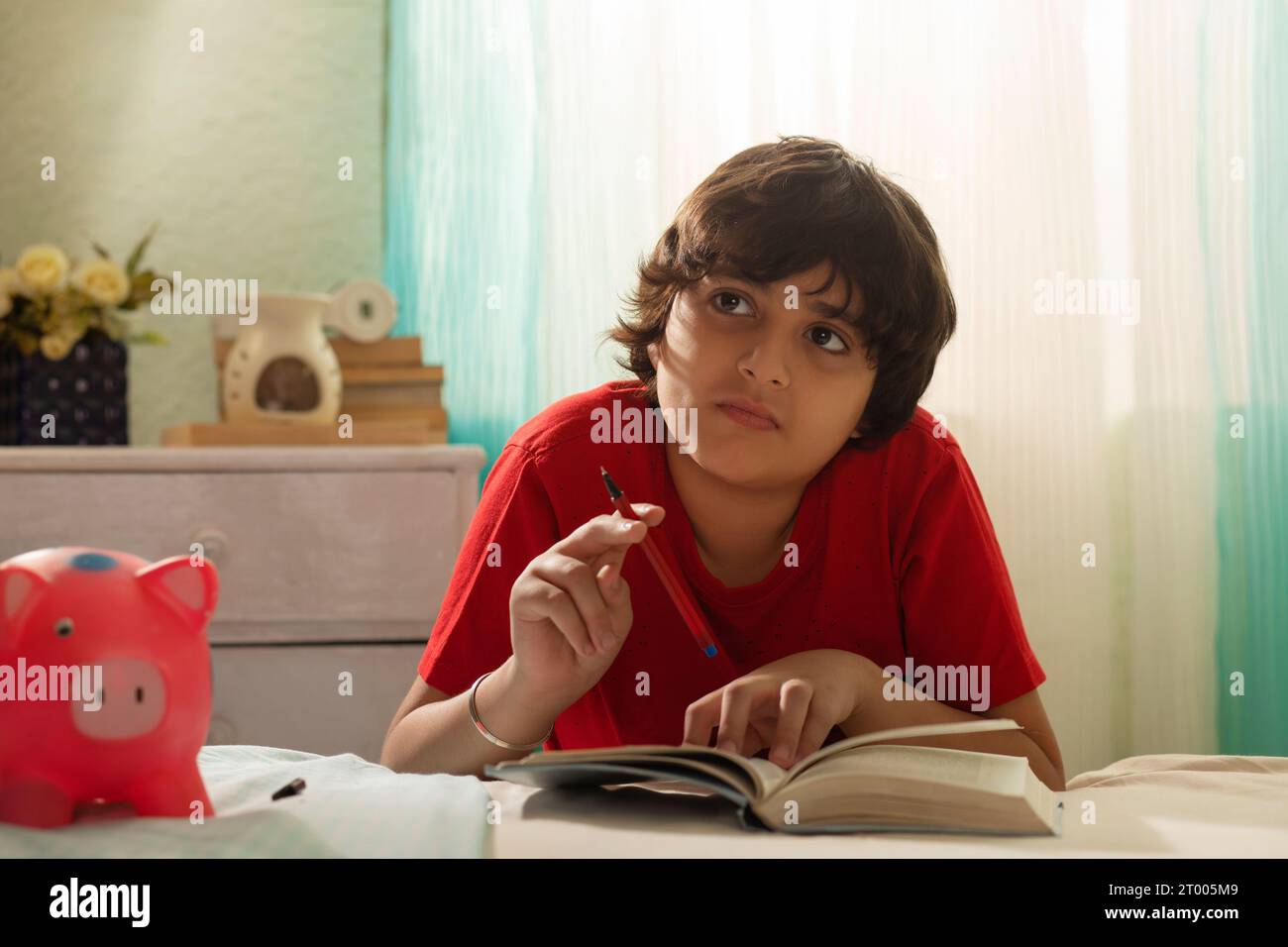 Boy thinking while reading a book on bed Stock Photo - Alamy
