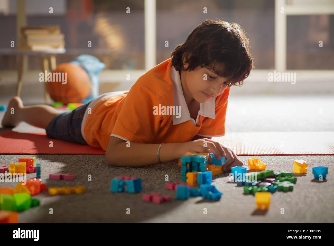 Boy playing with toy blocks while lying on floor Stock Photo - Alamy