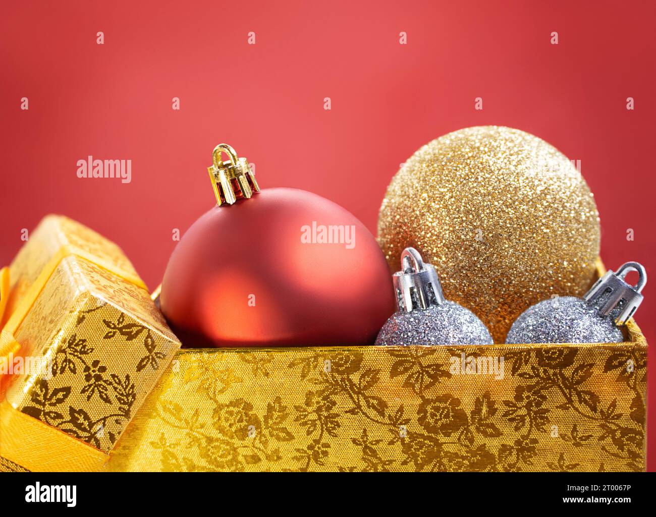 Christmas red, gold, silver balls in open yellow box on red background ...
