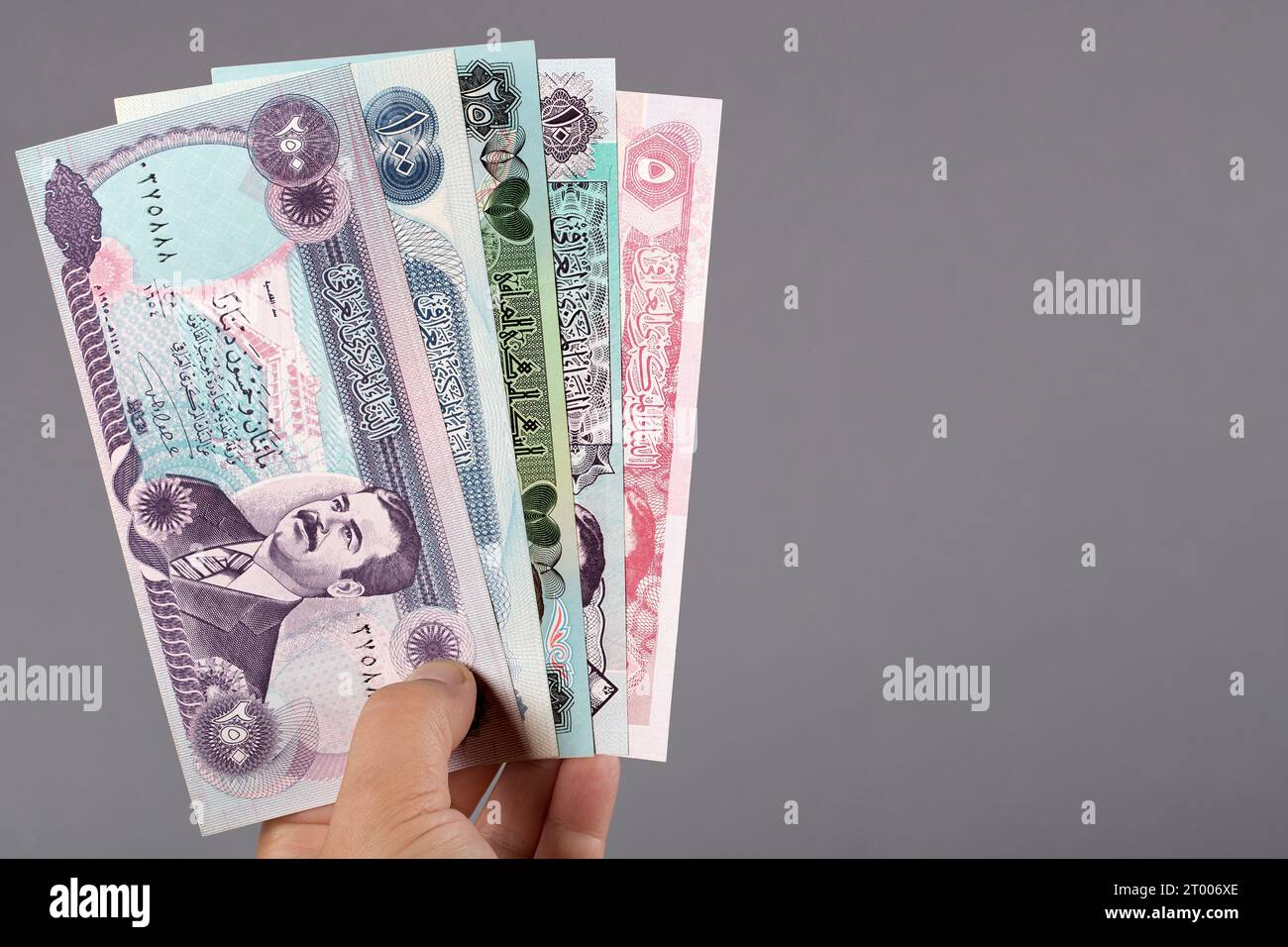 Old Iraqi money in the hand on a gray background Stock Photo - Alamy