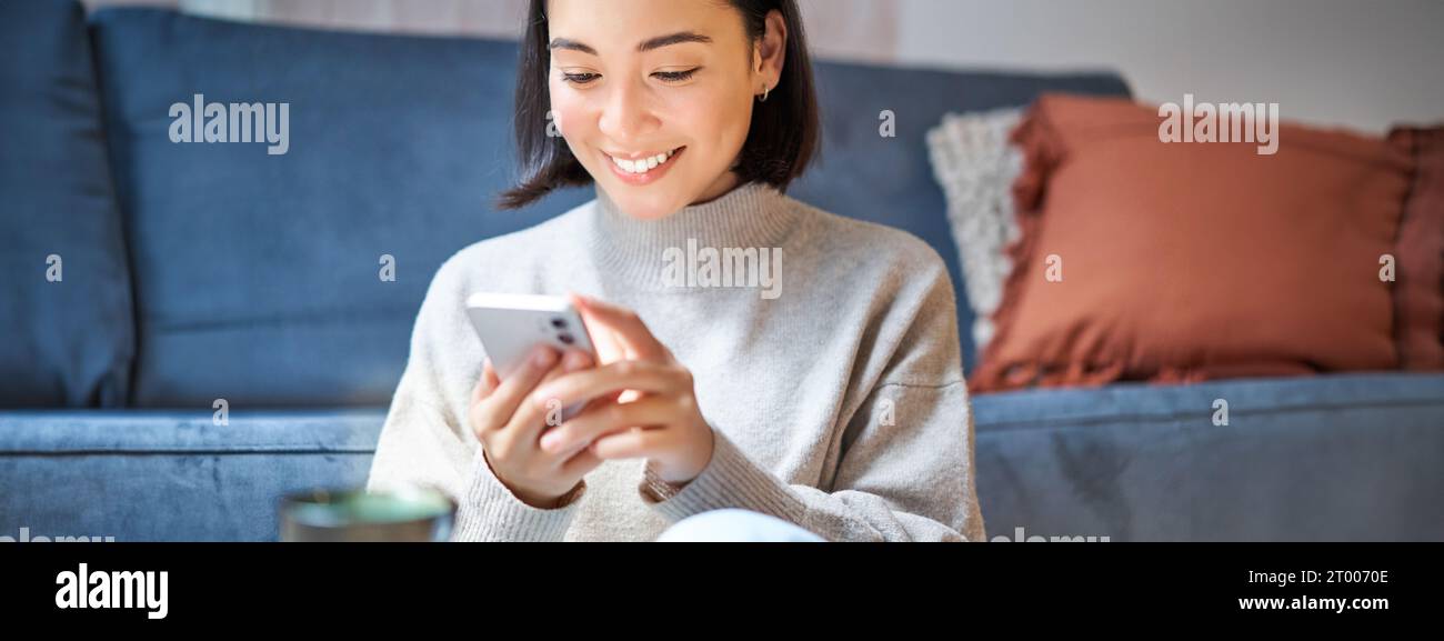 Technology and people. Young stylish asian woman sits at home with her ...