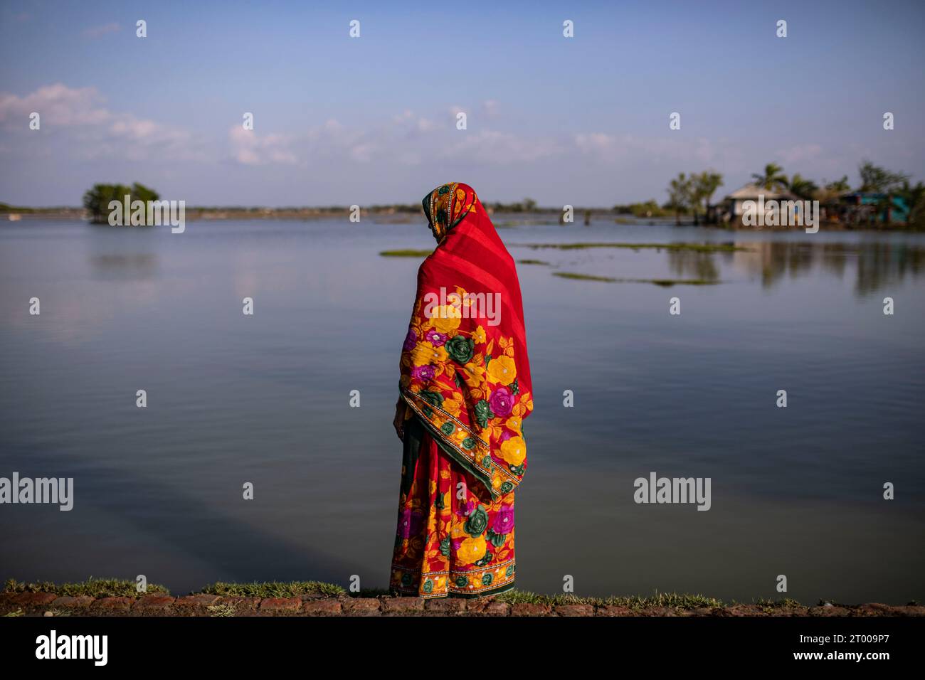 A woman stands beside a desiccated floodplain at Gabura union in ...