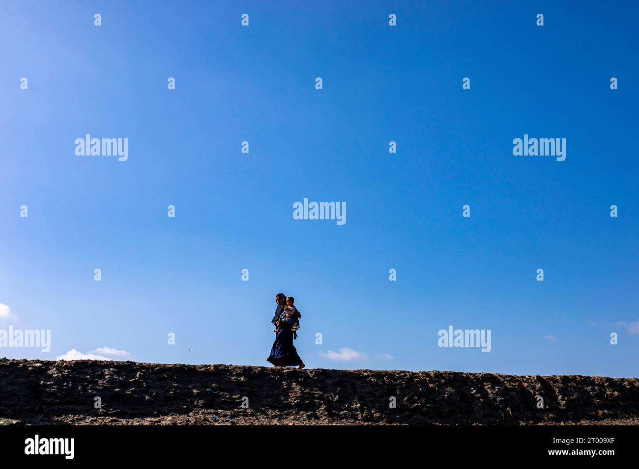 A woman walking tbrough an embankment on the bank of Kholpetua River ...