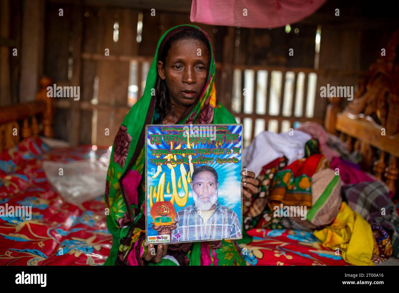Mosammat Rashida holds her husband's photo inside her home at Gabura in ...