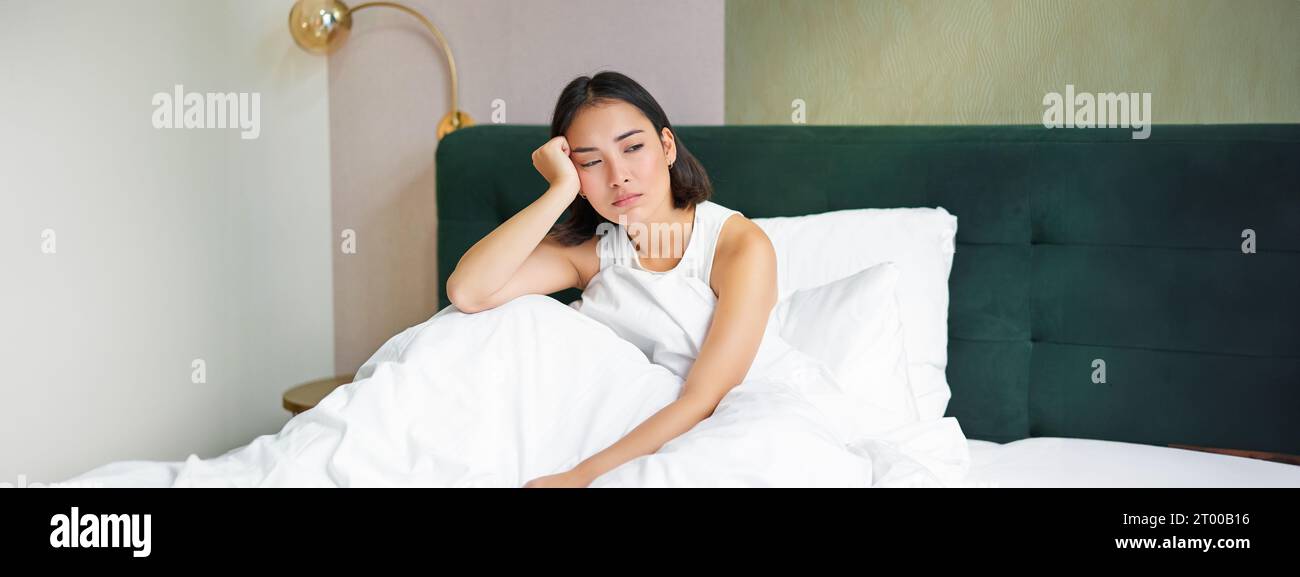 Portrait of sad young woman waking up, feeling bad, wants to sleep ...