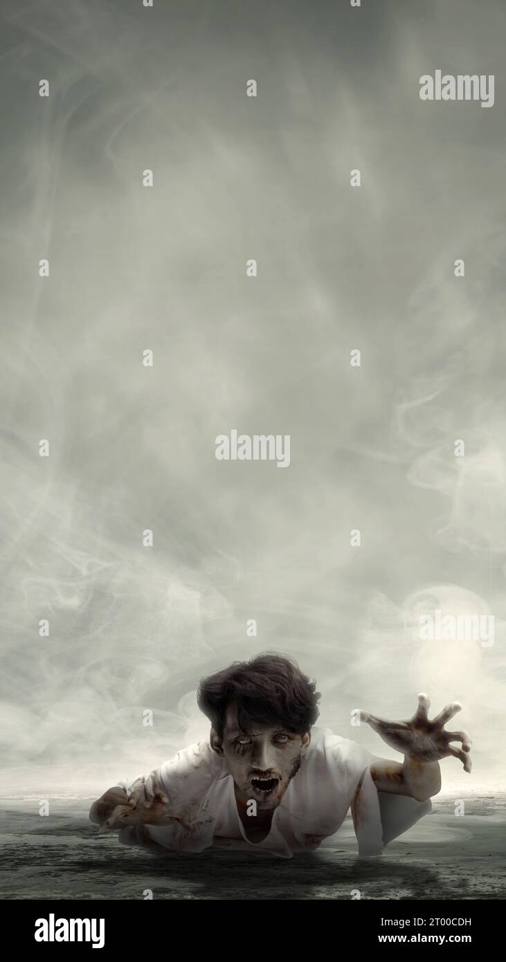 A scary zombie with blood and wounds on his body crawling with a dark ...