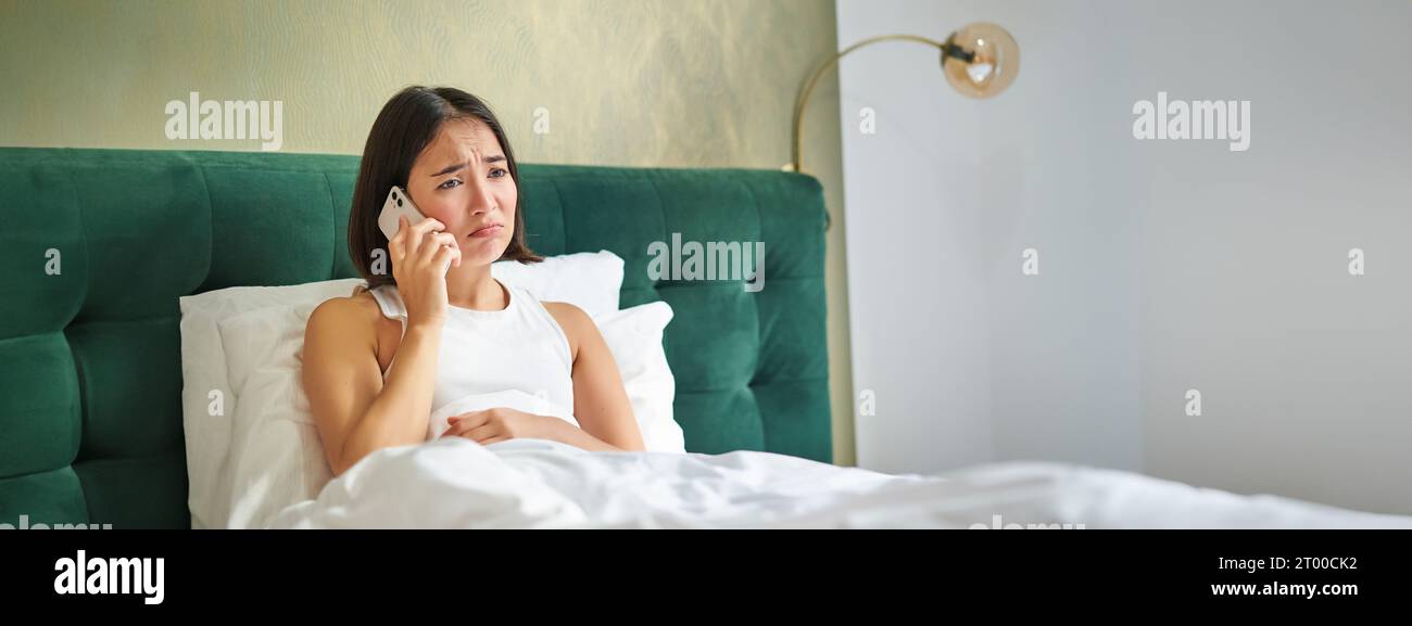 Portrait of concerned asian woman holding mobile phone, receive bad ...