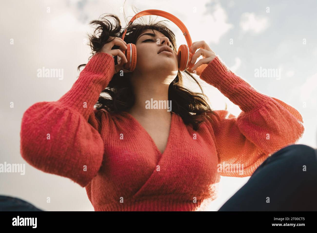 Low-angle shot of a young brunette woman with straight hair, about to ...