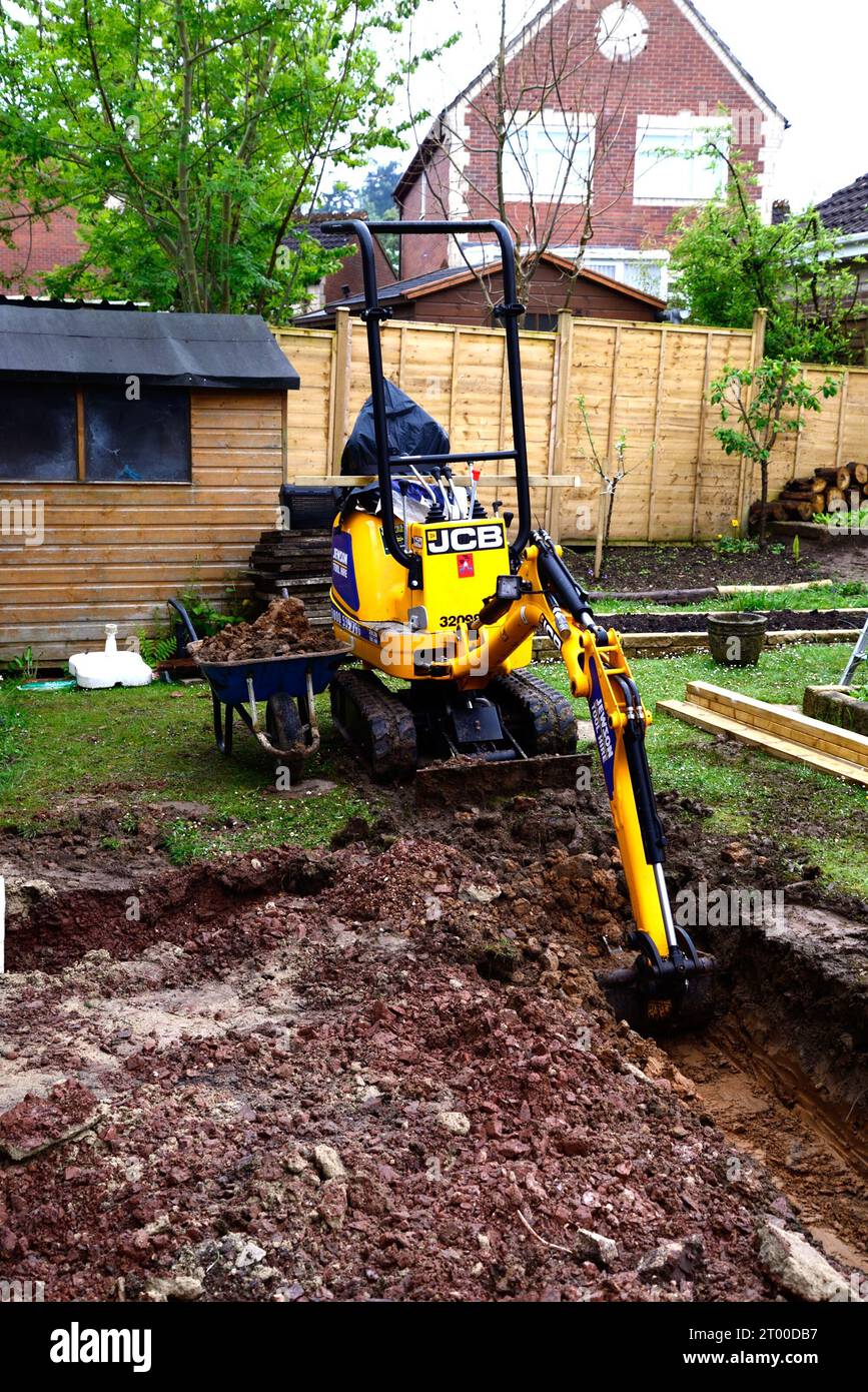 Mini digger parked in a garden being used for digging out ground to ...