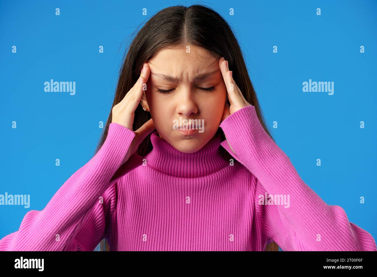 Teen girl suffering from headache on blue background Stock Photo - Alamy