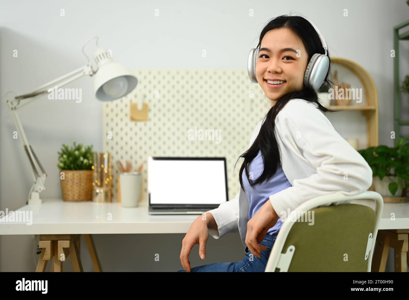 Friendly young woman sitting in front of laptop monitor and turning to ...