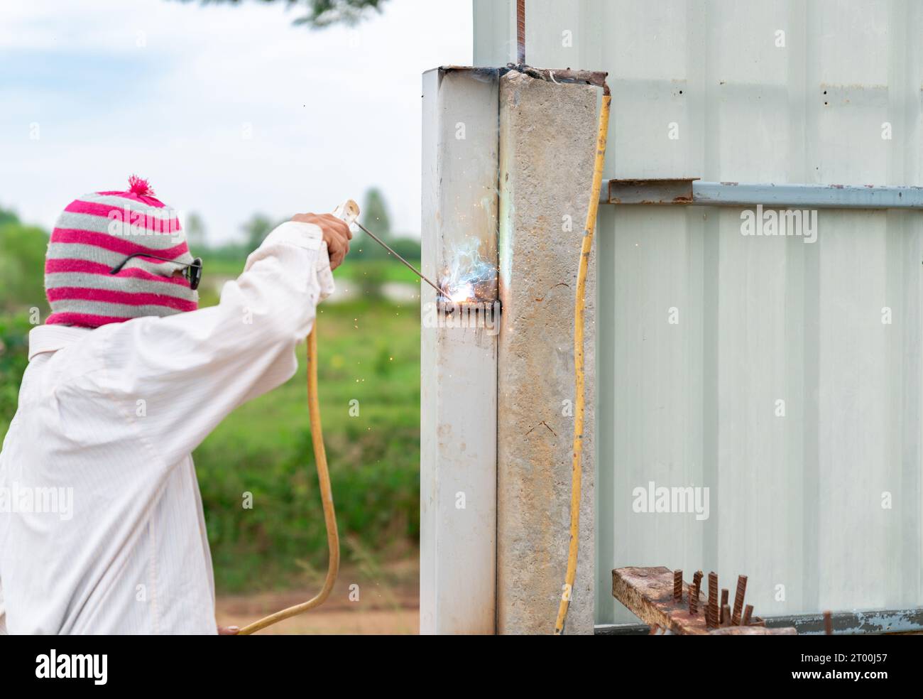 Worker welding steel pole for fence in building site Stock Photo - Alamy