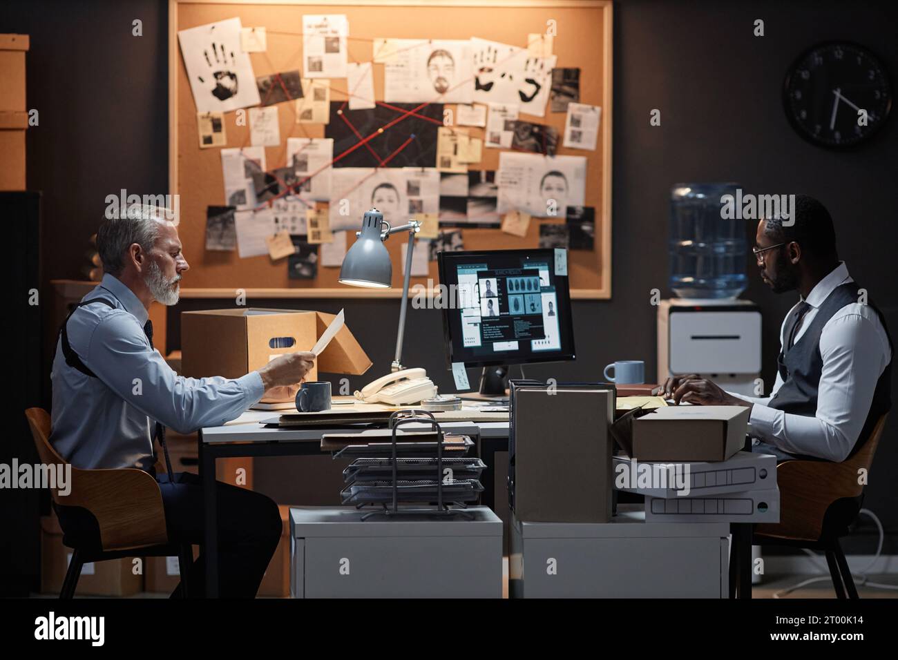 Side view portrait of two police detectives sitting at desk in office ...