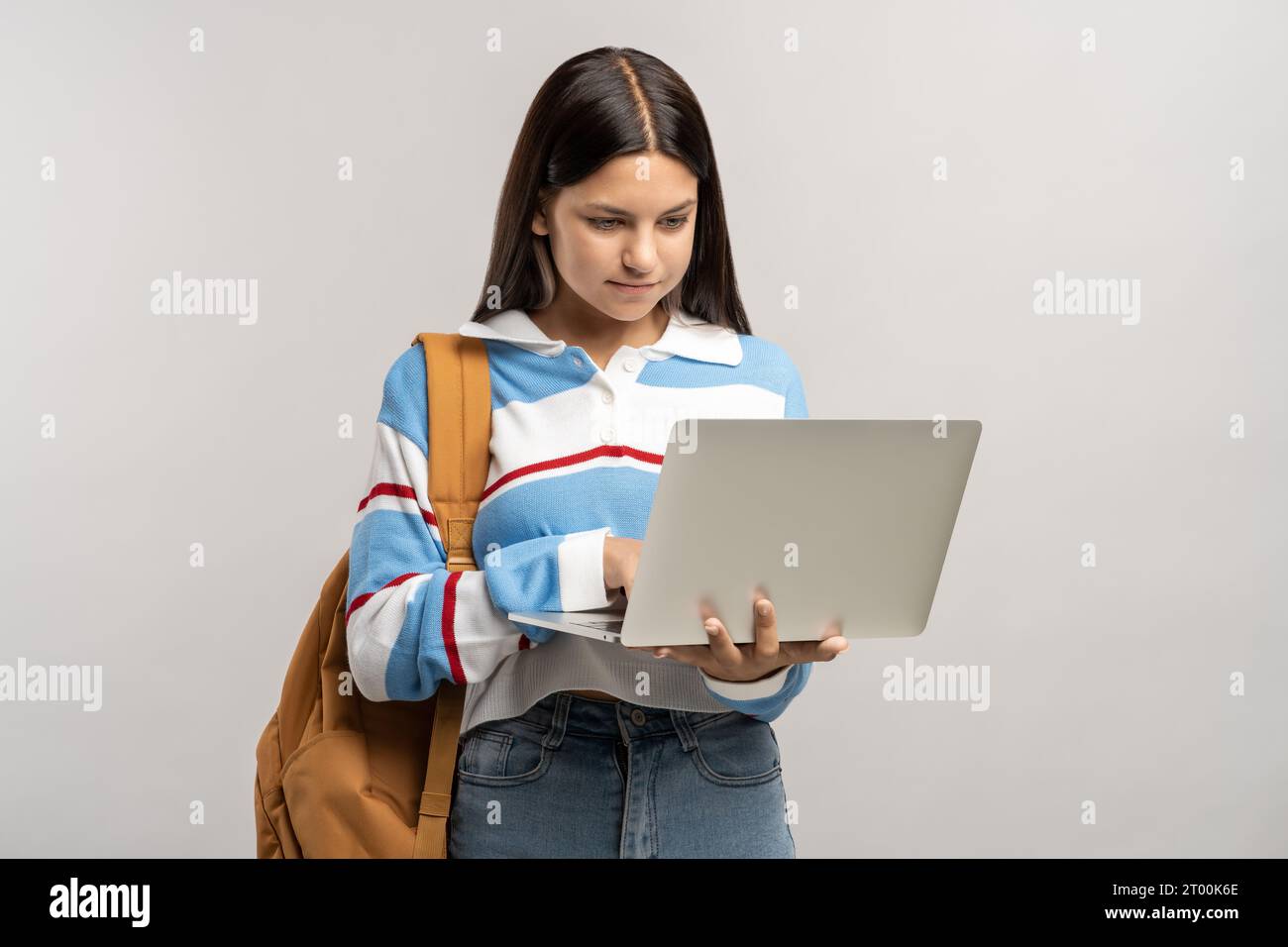 Interested student teen girl with backpack looking at laptop screen on ...