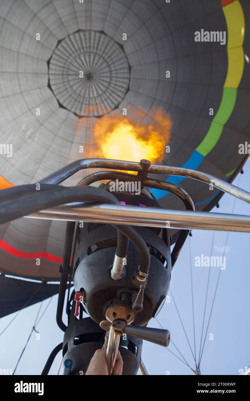 Hot air balloon pilot operating the burners. Low angle inside view ...
