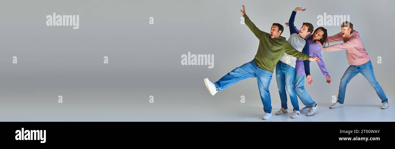 playful friends in casual street attire having fun on grey backdrop ...