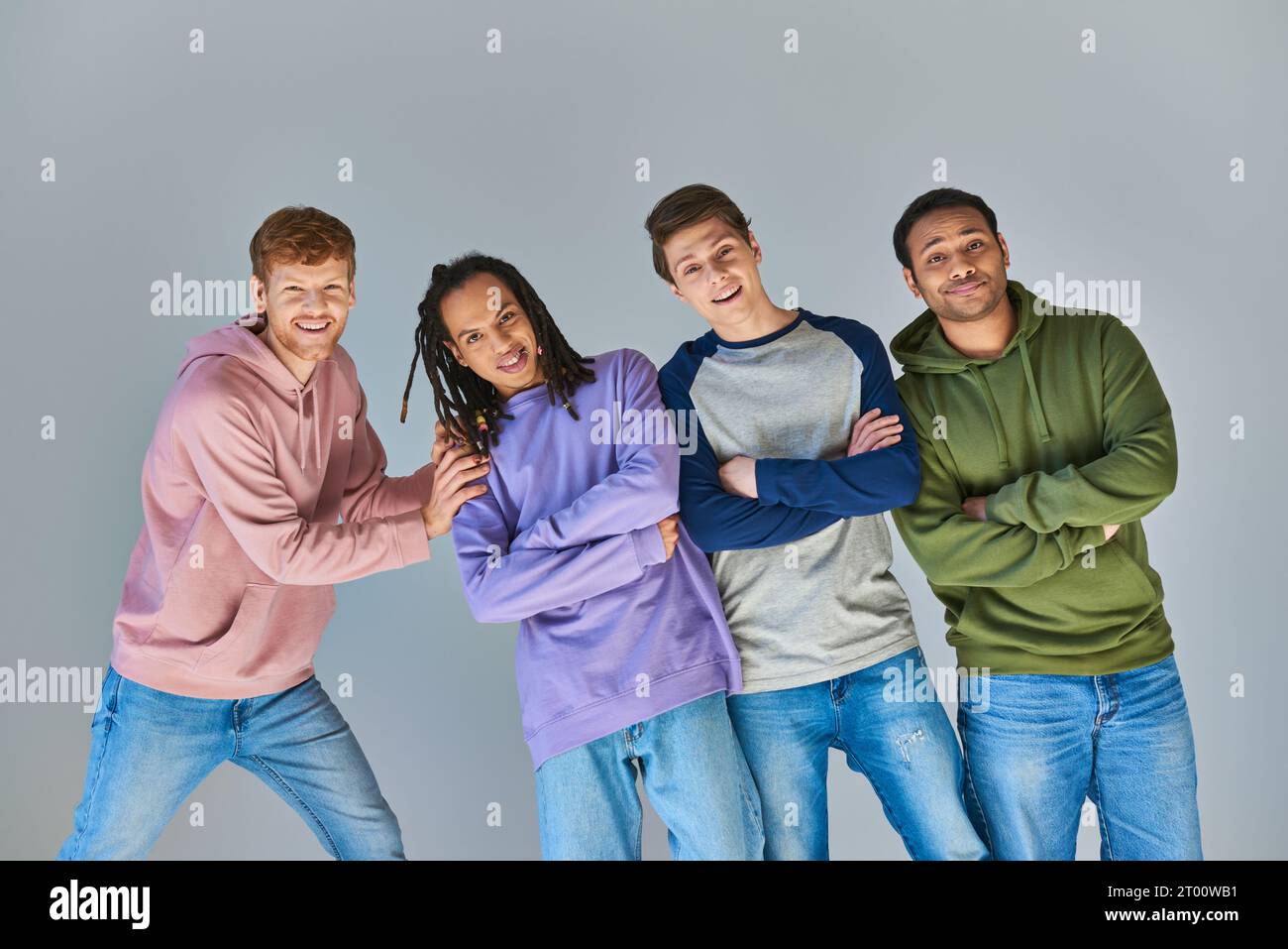 four cheerful men in casual outfits smiling at camera posing on grey ...