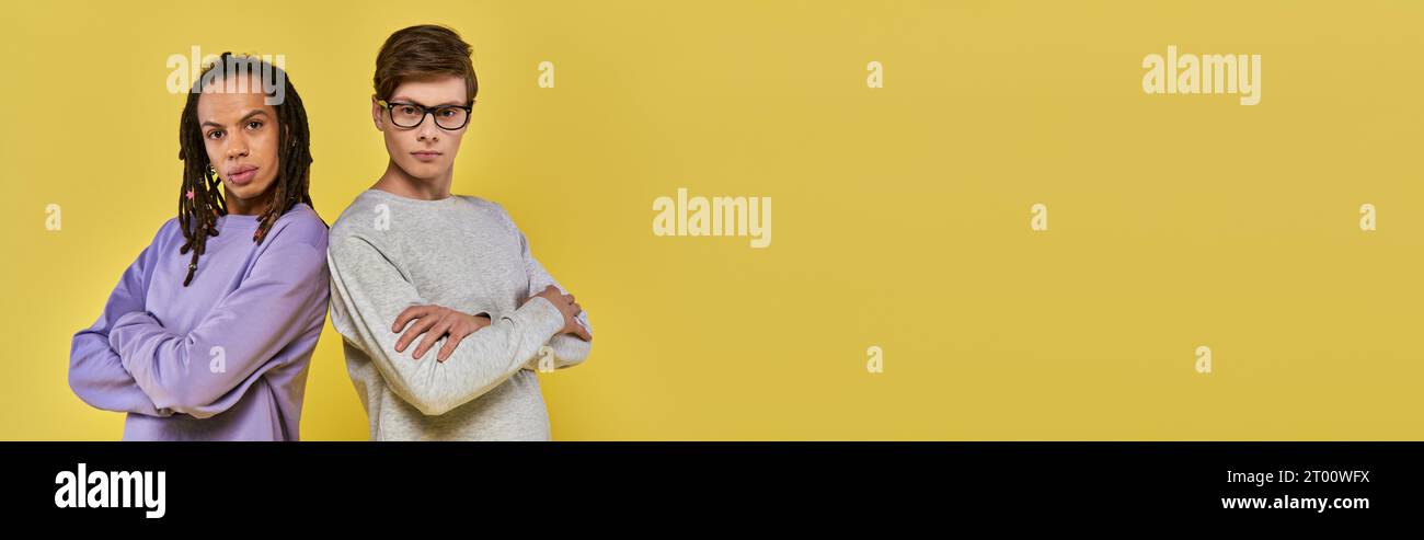 two serious handsome friends in casual attire standing back to back ...