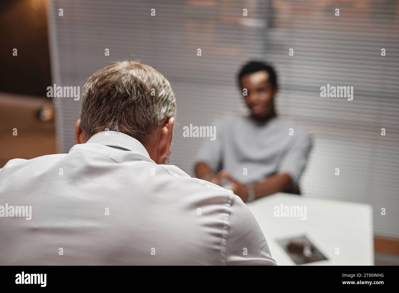 Back view of white haired detective interrogating criminal suspect in ...