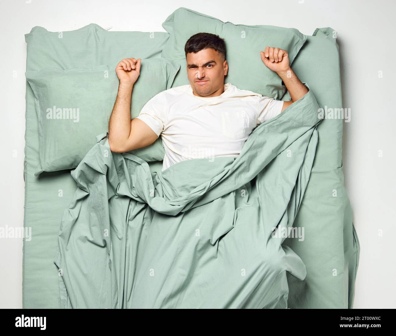 Young attractive confused man lying on his back looking to camera ...
