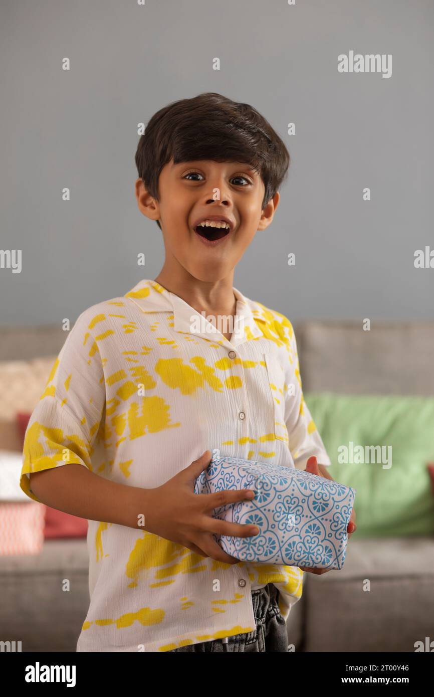 Portrait of a surprised boy holding a gift Stock Photo - Alamy