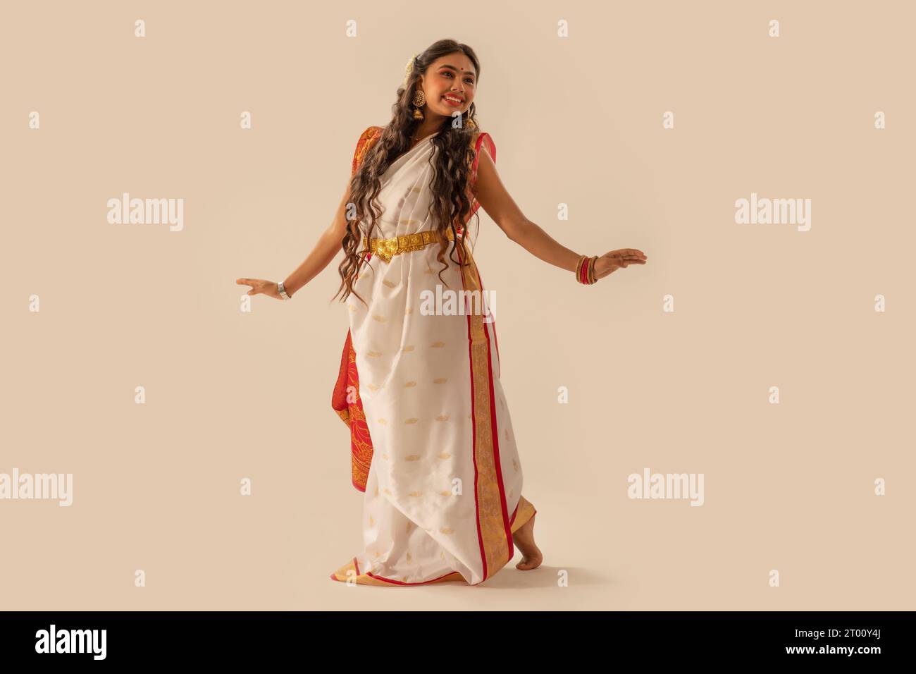 Portrait of Bengali woman in traditional outfit dancing against white ...