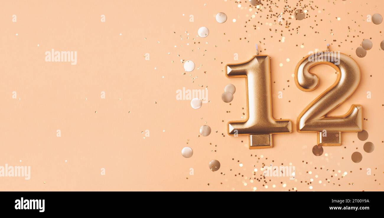 Gold candles in the form of number twelve on peach background with ...
