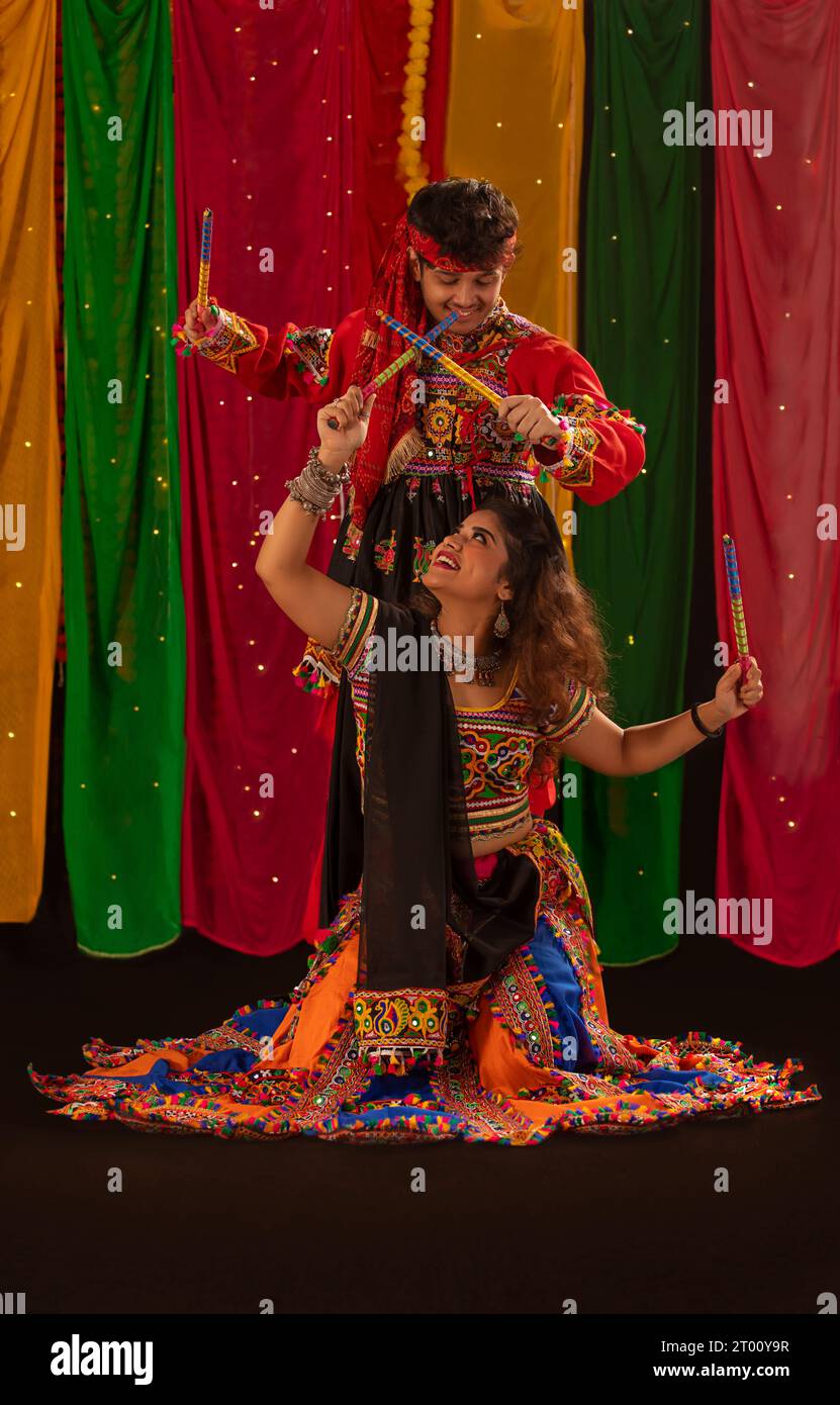 Indian couple dressed in cultural attire doing garba folk dance with ...