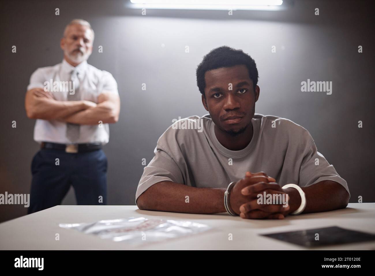 Portrait of Black young man as criminal looking at camera in prison ...