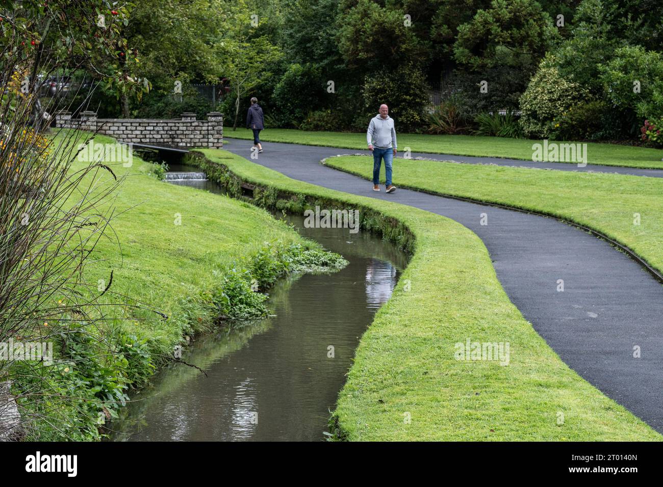People walking along a footpath next to a river stream flowing through ...