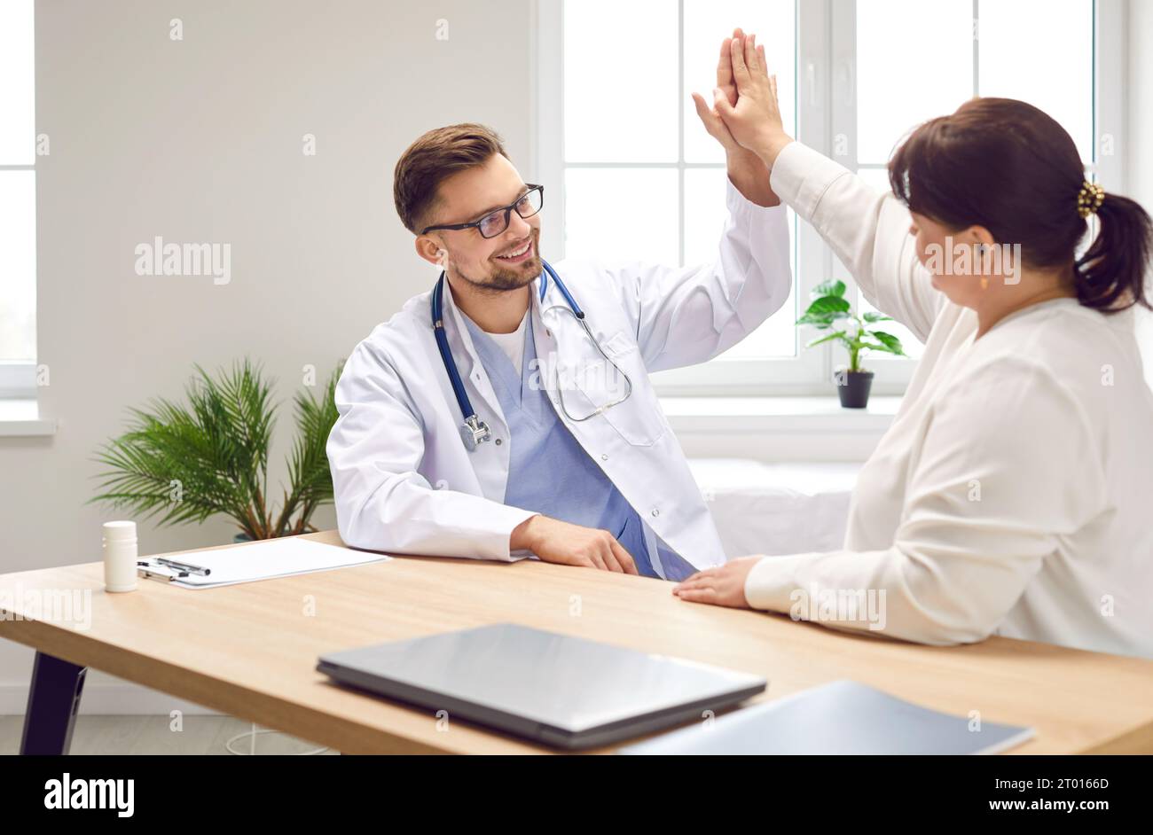 Young happy male doctor giving high five to a fat patient reaching ...