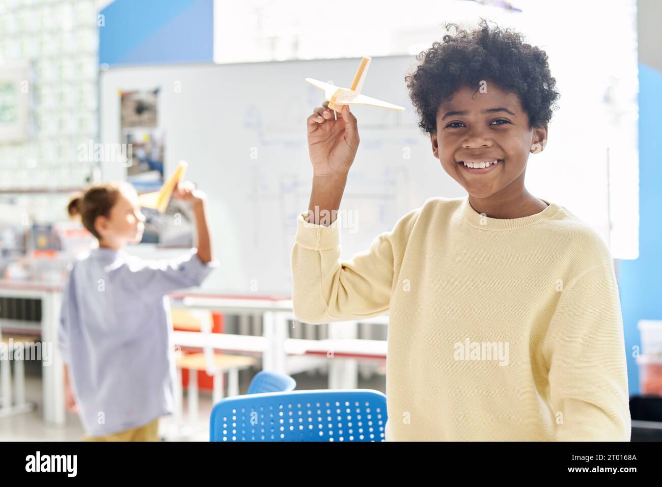 Positive kid playing with airplane model he glued in aeromodeling class ...